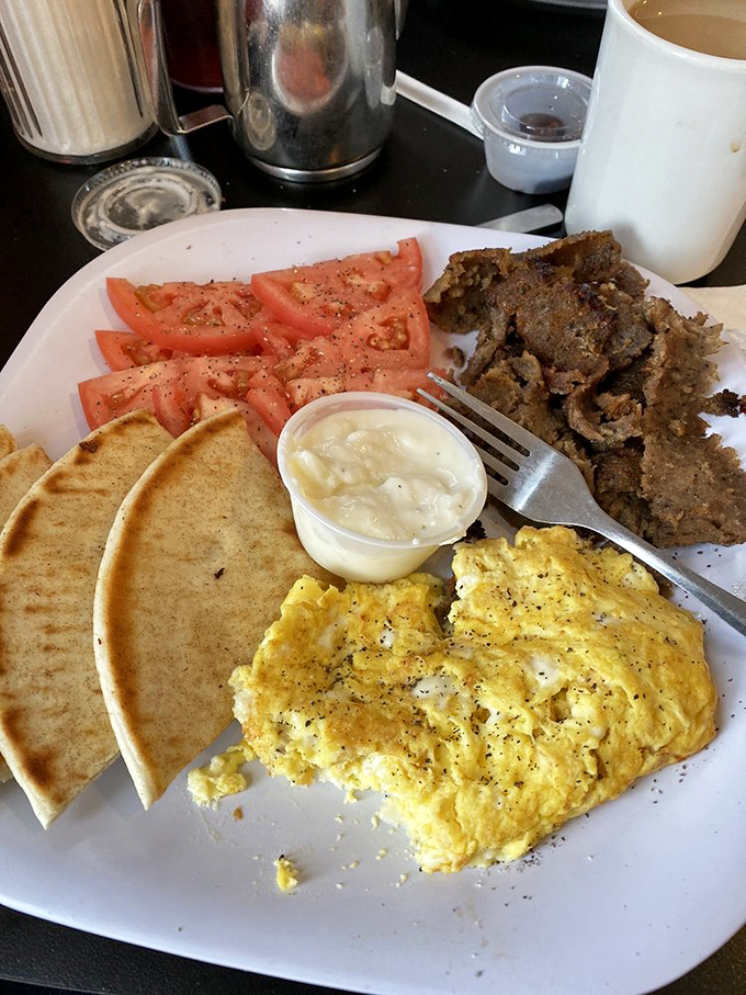 A breakfast platter that speaks the universal language of "you won't need lunch today" – eggs, pita, and seasoned meat in perfect harmony.