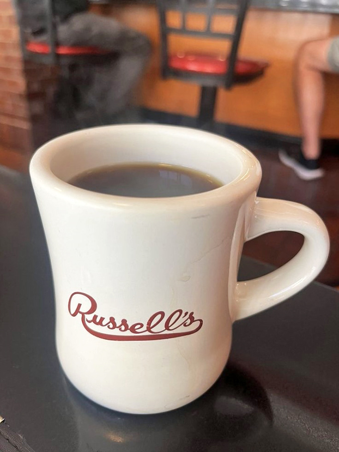 The sturdy white mug emblazoned with "Russell's" isn't just holding coffee—it's holding liquid motivation for your entire day.