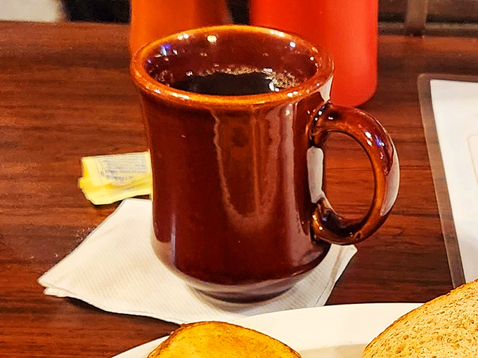 The classic brown ceramic mug—unofficial vessel of serious diner coffee. Where refills are frequent and conversations flow as smoothly as the caffeine into your bloodstream.