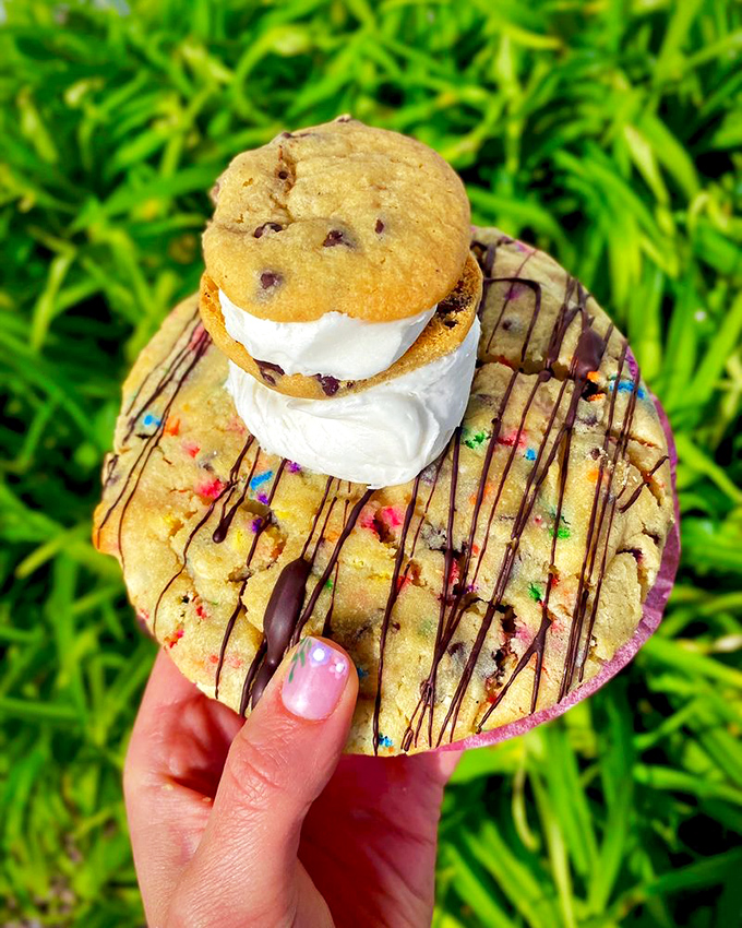 Cookie inception! A mini chocolate chip cookie riding atop its larger counterpart, drizzled with chocolate – because one cookie layer is never enough.
