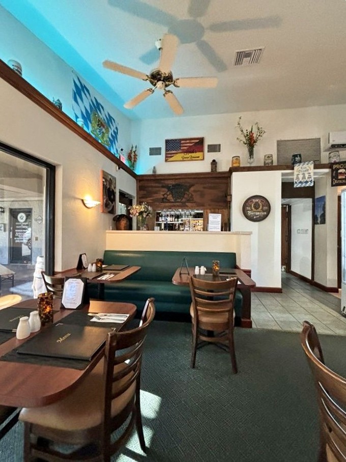 The dining area balances German tradition with Florida practicality—wood tables, teal booths, and enough ceiling fans to keep your schnitzel experience sweat-free.
