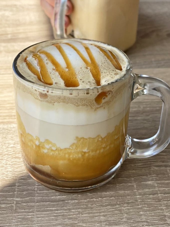 Coffee artistry that makes Monday mornings bearable—caramel drizzle creating a Jackson Pollock masterpiece in a mug.