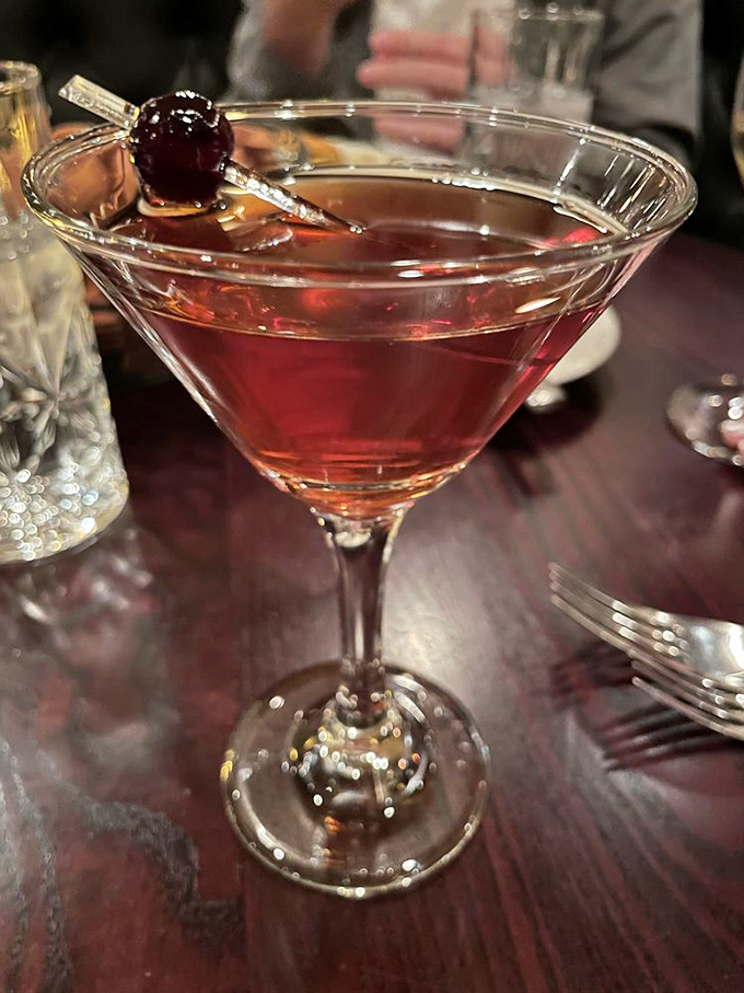 This isn't just a cocktail – it's liquid history in a glass, garnished with a cherry that's seen more sophistication than most of us on our best day.