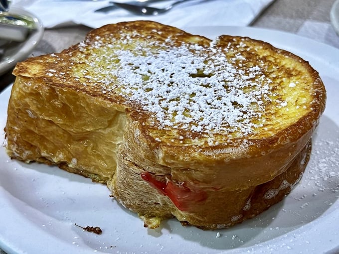 French toast that's dressed up for the occasion—powdered sugar snowfall on a crispy golden landscape. The jam peek-a-boo is just showing off.