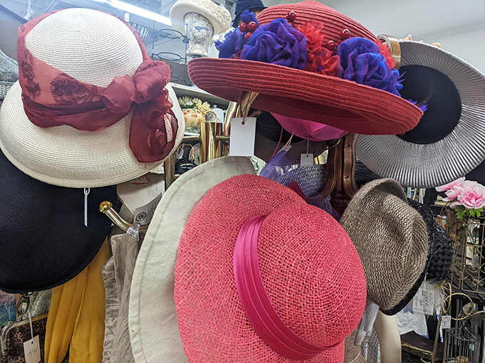 A garden party of vintage hats blooms on display stands—from demure cream straws to that show-stopping red number with purple flowers.