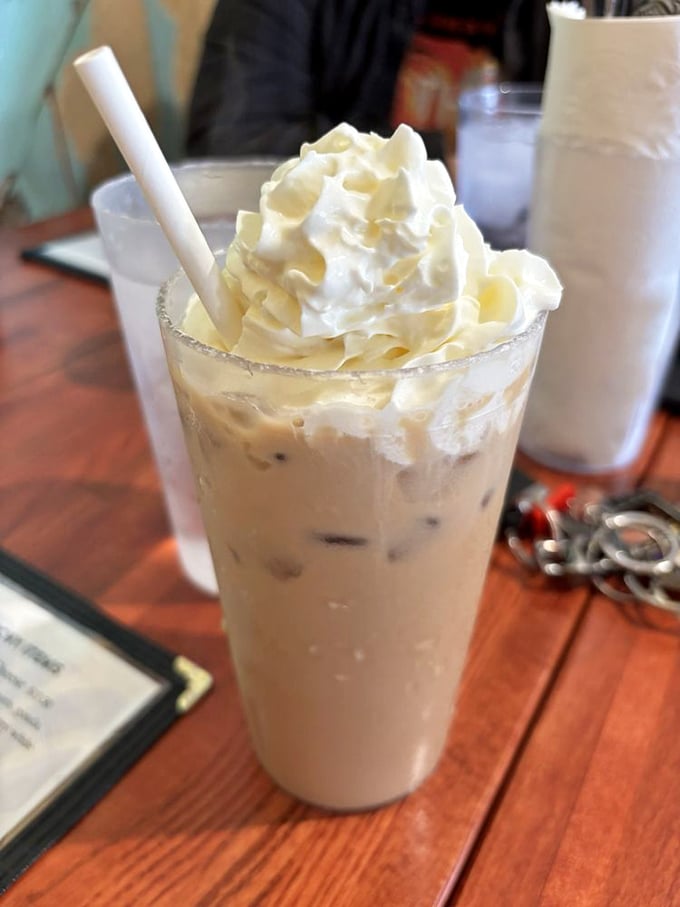 The iced coffee that makes you question your relationship with hot beverages—topped with a cloud of whipped cream that deserves its own zip code.