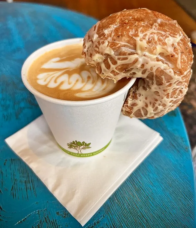Coffee and pastry, the Fred Astaire and Ginger Rogers of breakfast—elegant latte art dancing beneath a glazed donut perched on the cup's edge.