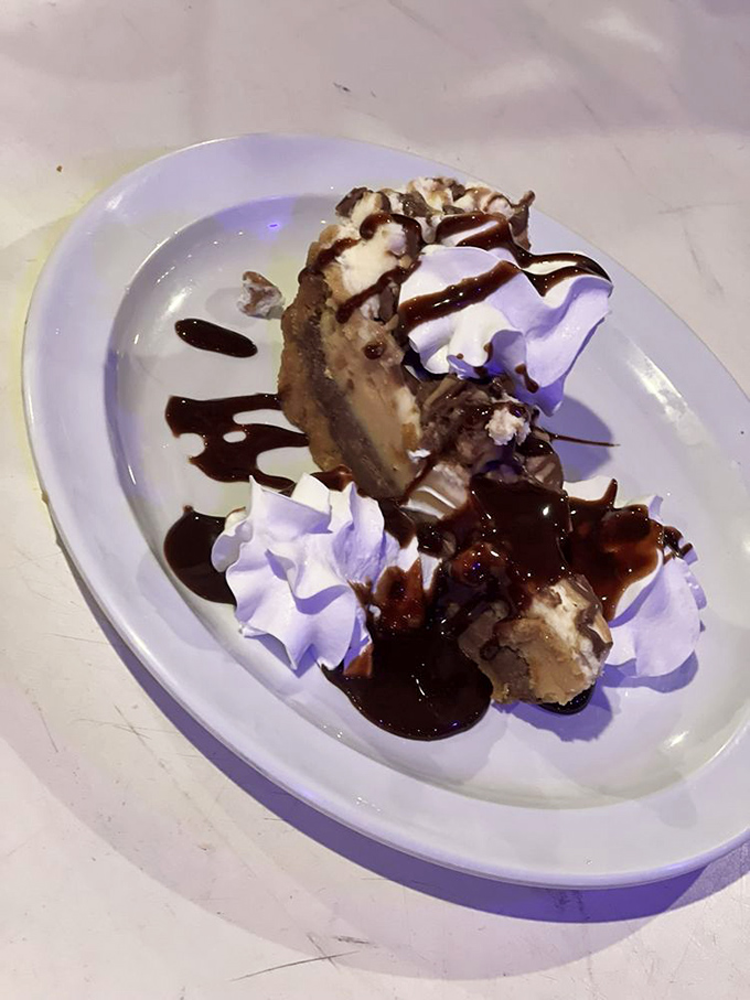This isn't just dessert – it's therapy on a plate. Peanut butter pie with chocolate drizzle and whipped cream mountains.