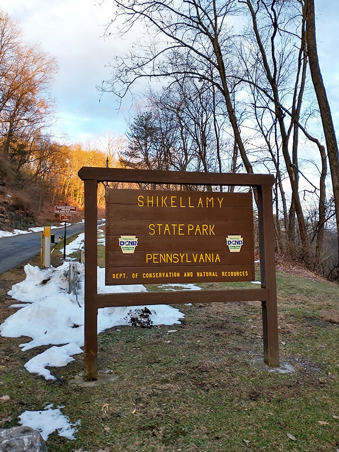 The official welcome sign stands like a friendly park ranger – sturdy, informative, and somehow managing to look good even with a dusting of snow.