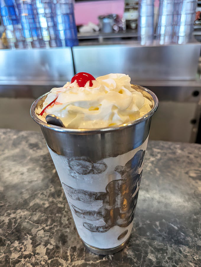 Not just a milkshake—a tower of vanilla dreams topped with whipped cream and a cherry that's basically wearing a crown.