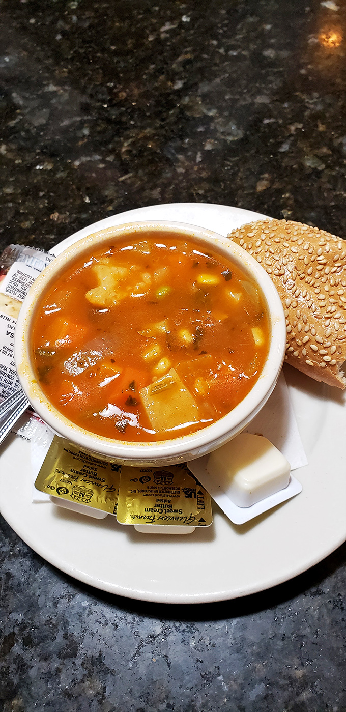 A bowl of vegetable soup that whispers, "Don't worry, winter won't last forever," served with the kind of roll that makes bread baskets jealous.