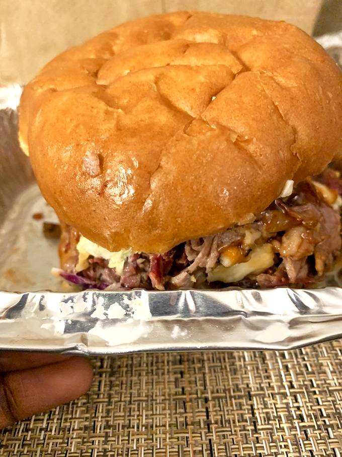 This sandwich proves that evolution exists – the classic Reuben took a detour through a smoker and emerged as something transcendent.