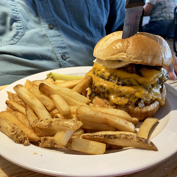 A burger that requires both hands and a strategy. With melted cheese cascading down like a yellow waterfall, this is lunch that demands your full attention.