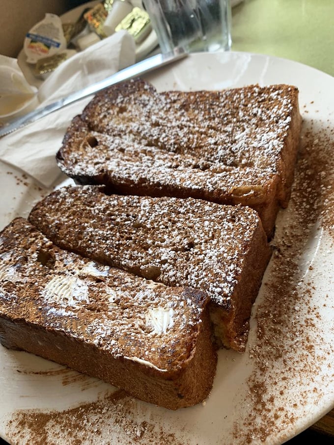 Challah French toast dusted with cinnamon—thick-cut slices transformed into a breakfast that straddles the line between meal and dessert.
