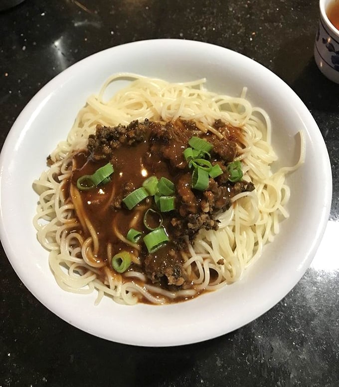 Dan dan noodles that would make a carb-counter weep with joy – tender strands supporting a savory meat sauce sprinkled with green onions for that perfect finish.