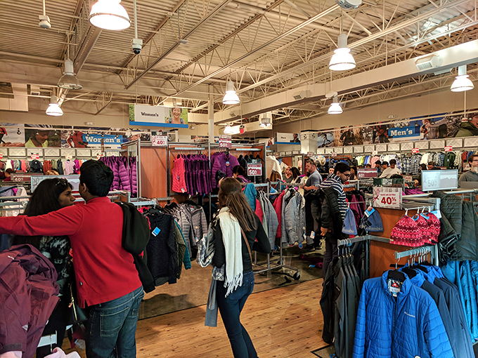 The thrill of the hunt in action—shoppers navigate racks of discounted outerwear like seasoned explorers tracking elusive bargains in their natural habitat.