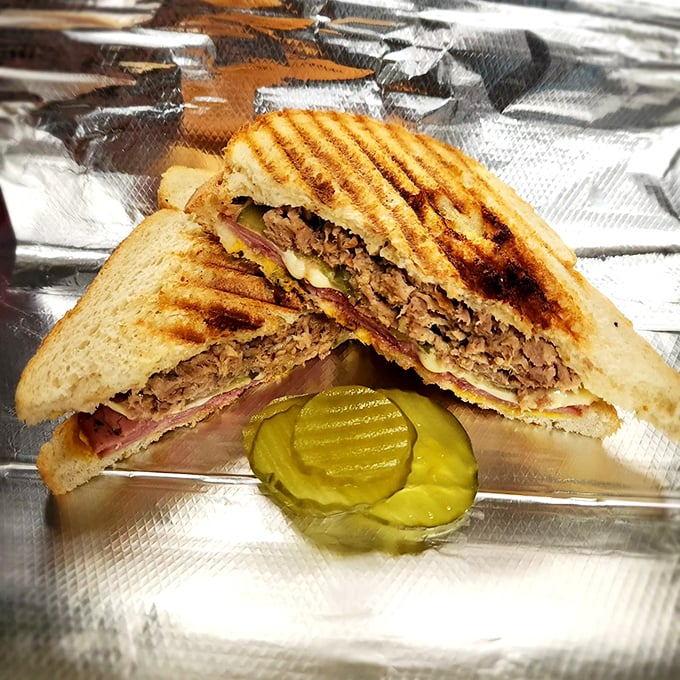A perfectly pressed Cuban panini with pickle sidekick. The grill marks aren't just for show—they're flavor tattoos.