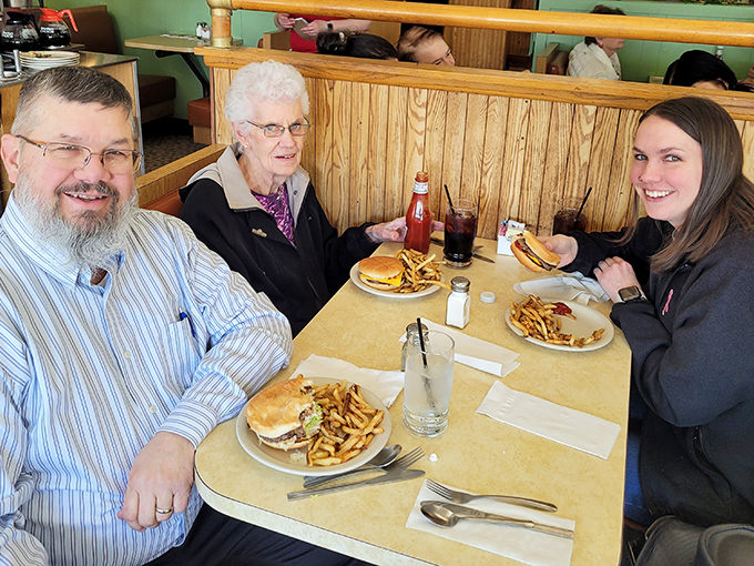 Three generations sharing burgers and fries—the universal language of "this is where we've always gone for the good stuff."