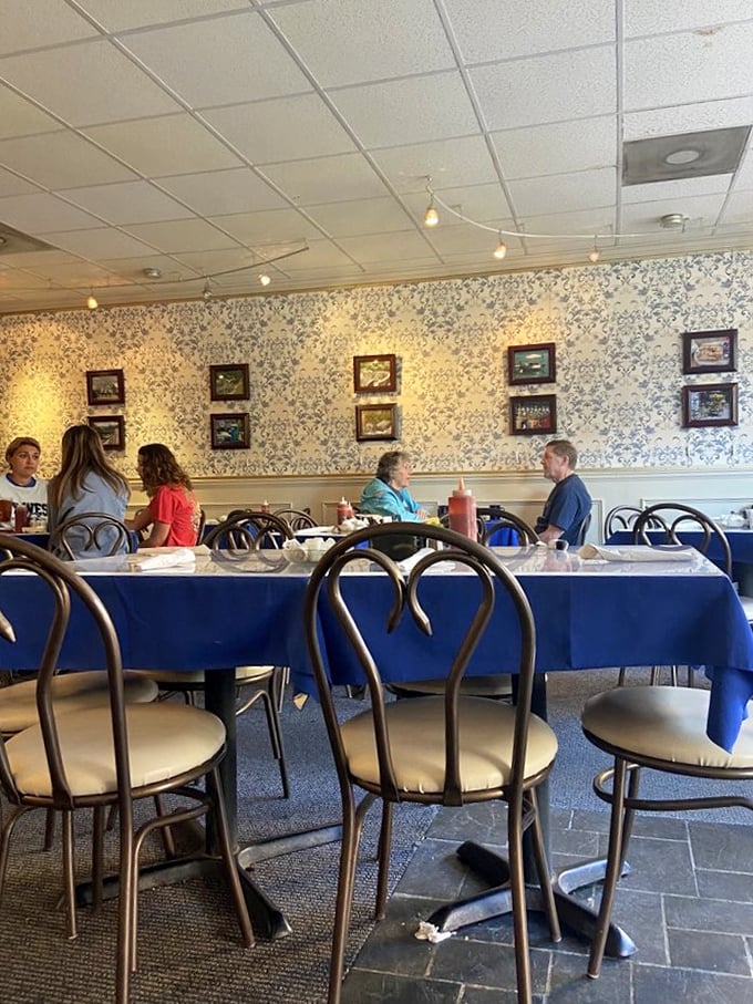 The dining room hums with conversation while blue tablecloths and floral wallpaper create the perfect backdrop for breakfast therapy sessions and coffee refills.