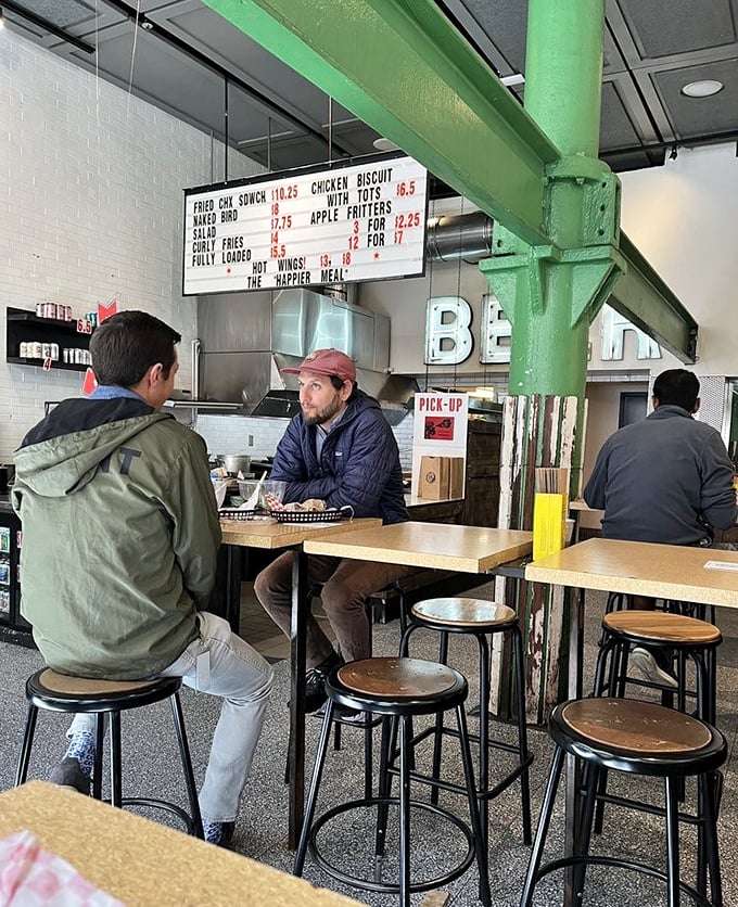 The green support beam adds industrial charm while diners engage in the sacred ritual of the lunch meeting—business talk punctuated by bites of exceptional chicken.