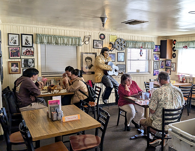 Diners enjoy their meals beneath the watchful gaze of a life-sized Elvis statue—because what's a 50s experience without The King holding court?