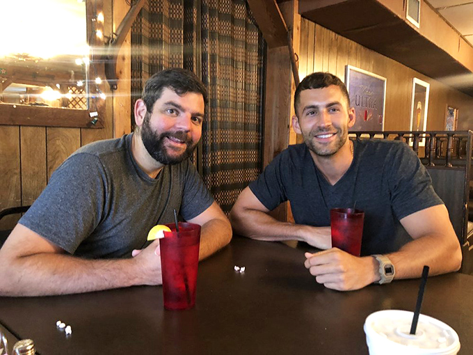 The wooden backdrop frames more than just diners—it captures the essence of genuine conversation fueled by good food and better company.