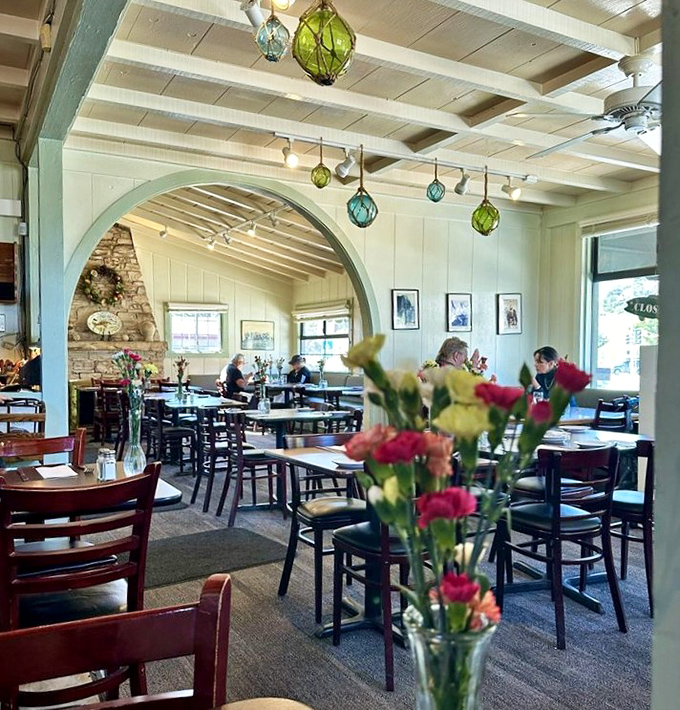 Colorful glass floats hang from white-beamed ceilings, creating a nautical charm that feels both authentic and inviting.