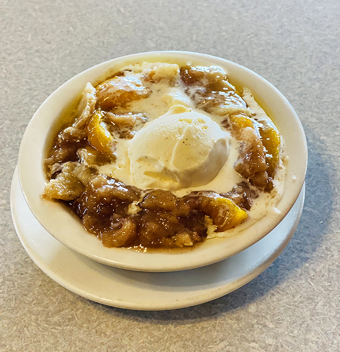 This isn't just peach cobbler with ice cream—it's what happiness would look like if it took physical form and landed in a bowl.