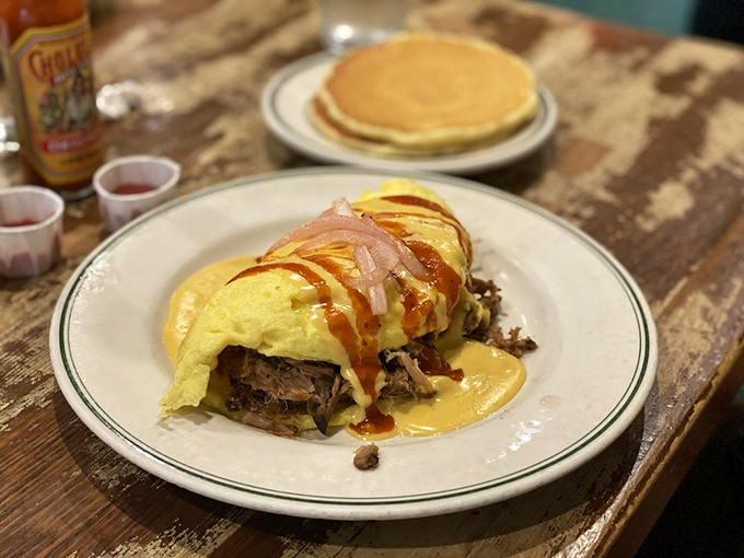 This omelet doesn't just contain ingredients—it embraces them, wrapping pulled pork in a golden egg blanket with sauce artfully drizzled on top.