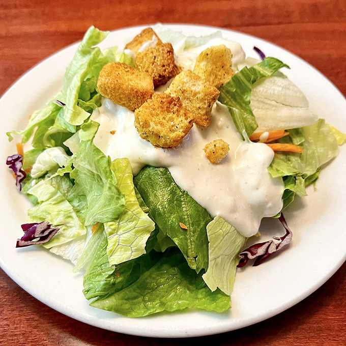A simple house salad that knows its role—bringing crisp, fresh contrast to the richness that's coming, with croutons that crunch like they mean business.