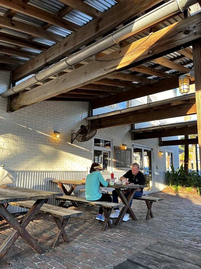 The outdoor seating area invites lingering conversations under wooden beams. Florida sunshine filters through, creating the perfect lunch backdrop.