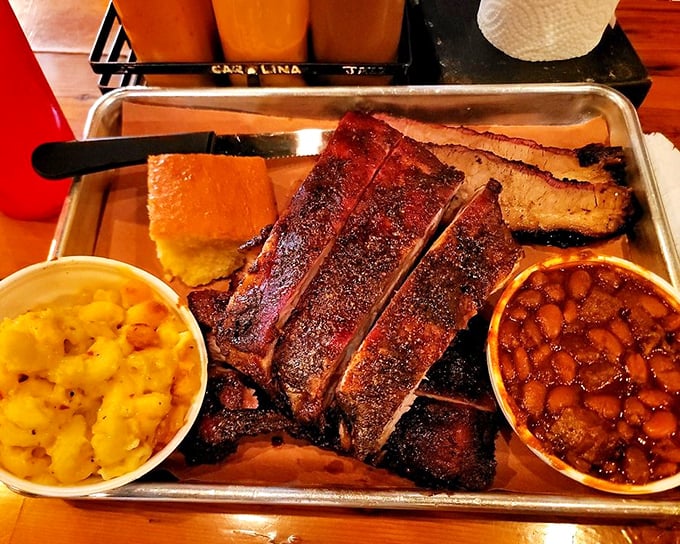 A metal tray bearing ribs, cornbread, and sides isn't just dinner—it's a love letter written in smoke and spice rub.