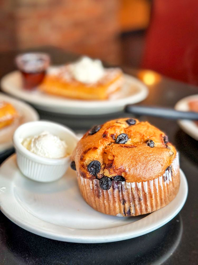 This blueberry muffin isn't just baked—it's architecturally designed for maximum berry distribution. The side of cream is just showing off.