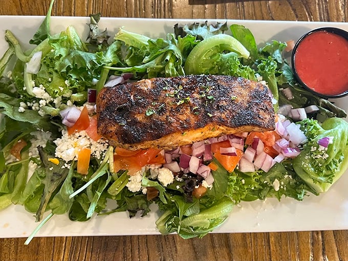 A perfectly blackened piece of fish resting on a bed of greens – proof that healthy eating doesn't have to feel like punishment.