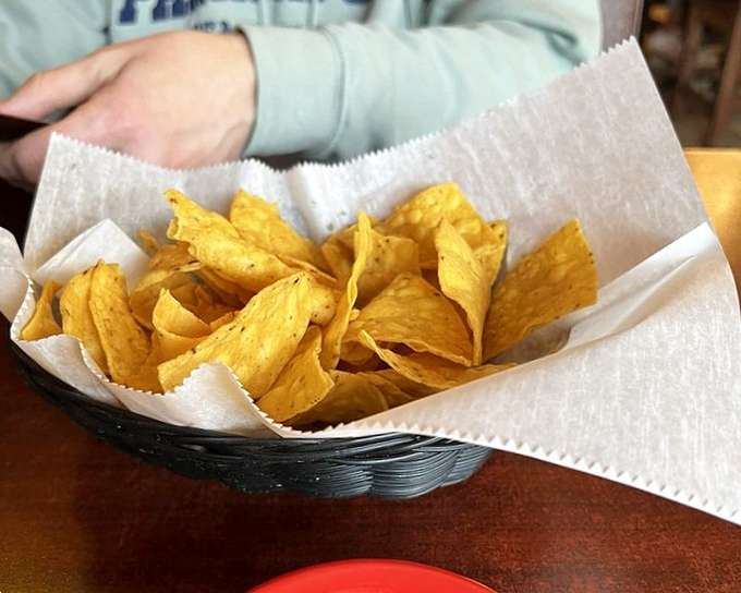Golden triangles of possibility—each chip a blank canvas awaiting its salsa destiny. The paper-lined basket isn't just serving chips; it's delivering happiness by the handful.
