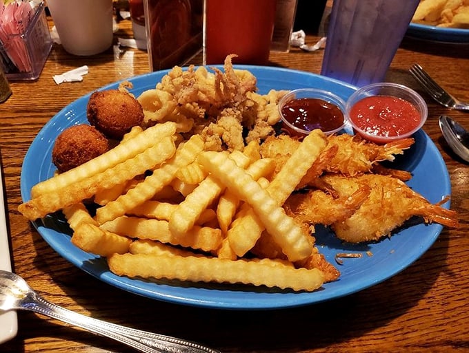 Blue plate special? More like blue plate spectacular! Crispy fries, golden shrimp, and hush puppies create the seafood trifecta of happiness.