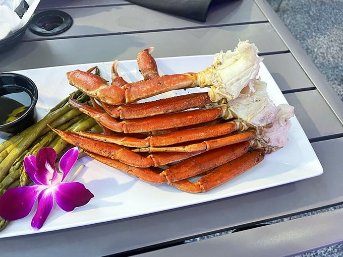 Snow crab legs arranged like nature's perfect architecture. The purple orchid isn't just garnish—it's a reminder you're dining somewhere special.