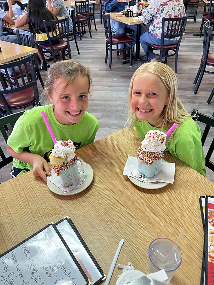 Joy served in milkshake glasses. Two young diners demonstrate the universal truth that sprinkles make everything more magical.