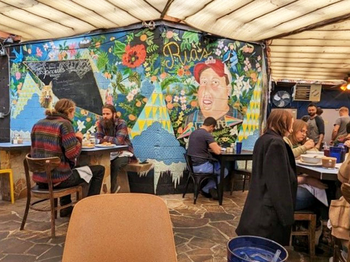 The covered patio feels like dining in an artistic friend's backyard. That mural isn't just decoration—it's a conversation starter between bites