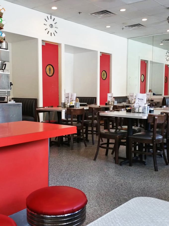The bright red accents against crisp white walls create that classic diner aesthetic that Instagram filters try desperately to replicate.