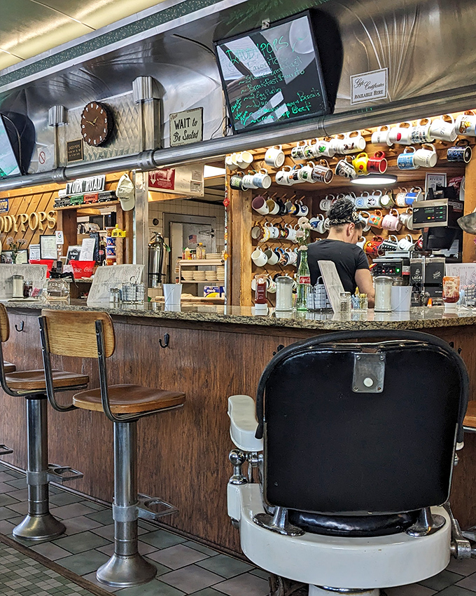 Coffee mugs hanging like trophies and a classic barber chair—this isn't just a diner, it's a museum of American comfort.