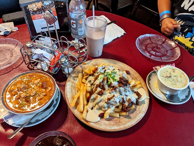 A table spread that tells a story: hearty gumbo, loaded fries smothered in cheese and meat, and a cup of something creamy calling your name.