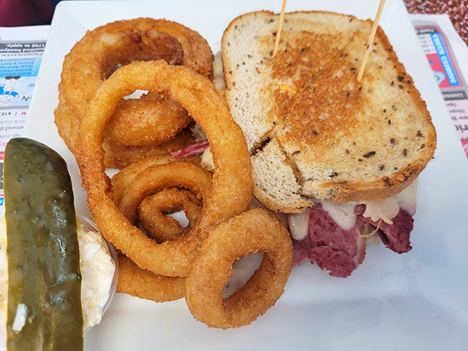 The Reuben sandwich—where corned beef meets sauerkraut in a dance as old as time, with those onion rings playing perfect wingman.