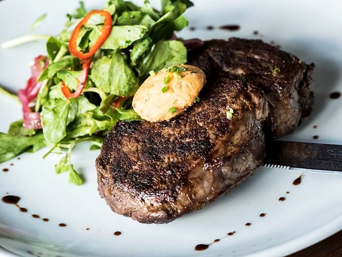 A perfectly seared steak with compound butter slowly melting into meat paradise—the kind of simple luxury that makes you forget you're technically eating on a boat.