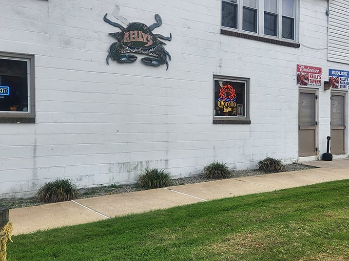 The unassuming white exterior of Kelly's Tavern, where that iconic crab sign promises more flavor than flash. Delaware seafood paradise found!
