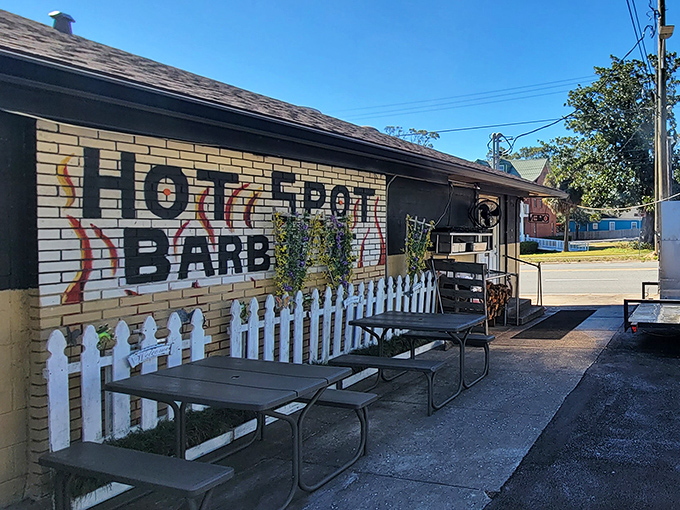 The unassuming yellow brick exterior of Hot Spot Barbecue is like a barbecue speakeasy – no fancy frills, just a white picket fence guarding smoky treasures within.
