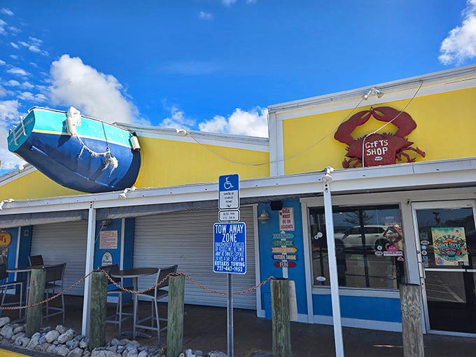 The iconic yellow and blue exterior of Crabby Bill's, where that boat on the roof isn't just decoration—it's a promise of seafood so fresh it practically swam to your table.