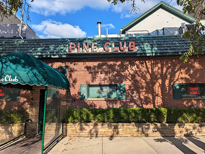 The iconic Pine Club exterior beckons with its vintage charm. That green-shingled roof and classic neon sign have been welcoming hungry Daytonians for generations.