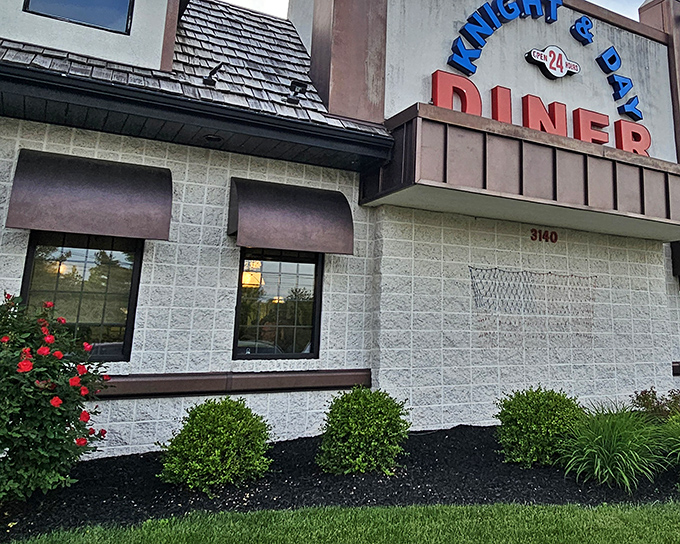 The classic diner entrance beckons with its no-nonsense charm. Colorful flower beds add a touch of warmth that says "come on in, we've been expecting you."