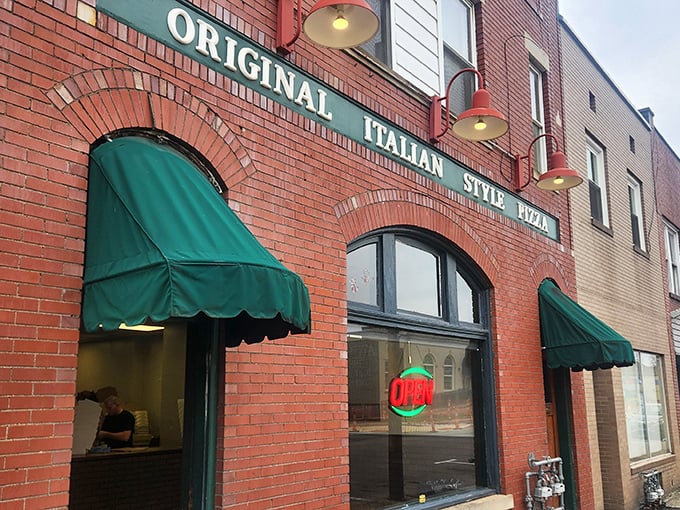 The iconic brick façade with green awnings doesn't scream "food destination," but locals know this unassuming storefront houses pizza worth committing minor traffic violations for.